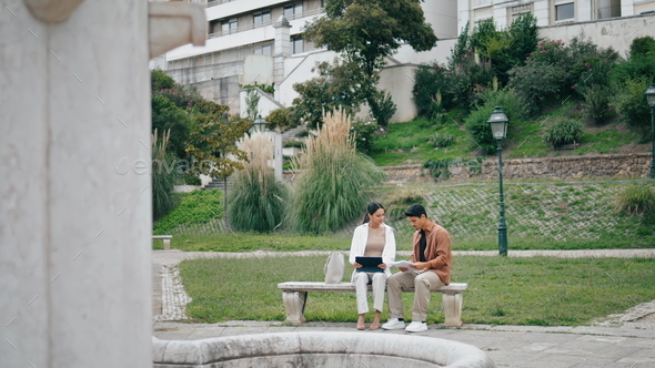 Busy students learning laptop on park bench. Inspired friends studying ...