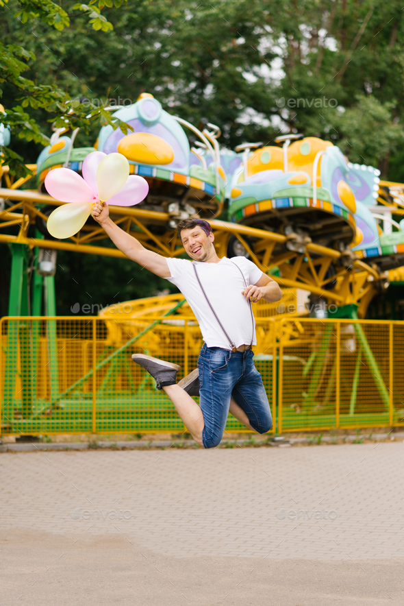 Funny Guy Holds a Bunch of Balloons in his Hands at Amusement Park ...