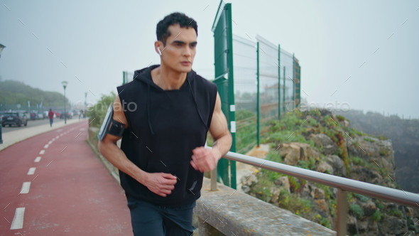 Confident athlete running morning track. Serious motivated man training ...