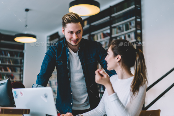 Excited guy discussing with friend collaborative project in library ...