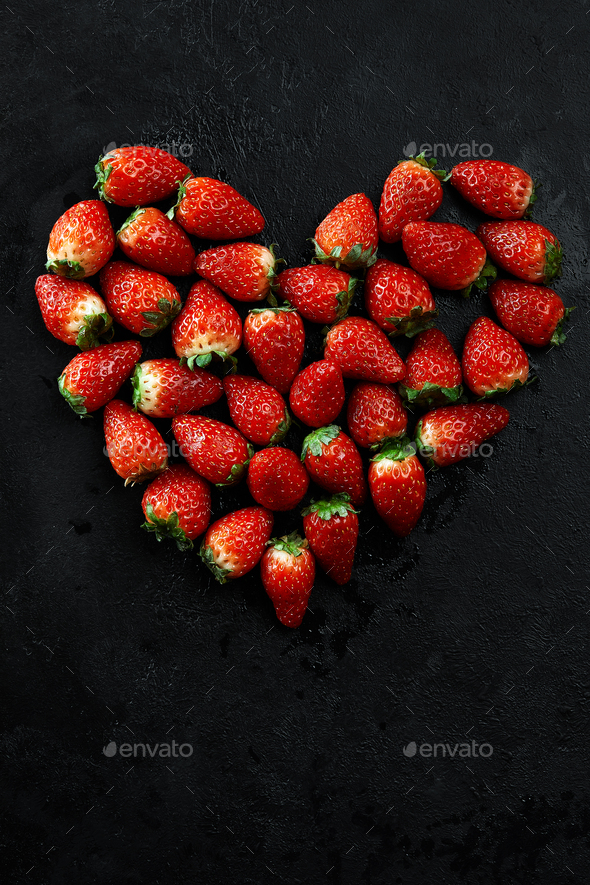 Fresh strawberries array heart shape on black background. Love concept ...