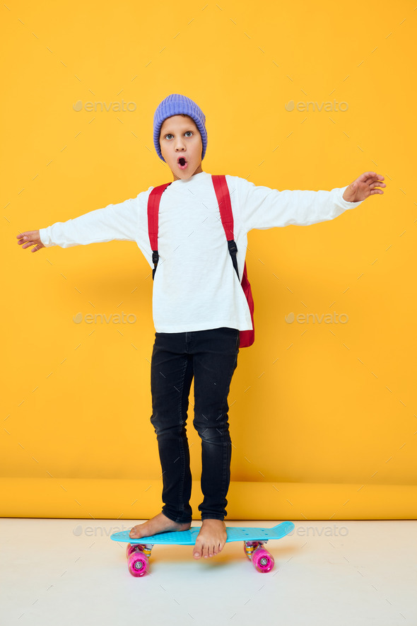 happy schoolboy rides a skateboard in a blue hat yellow color ...