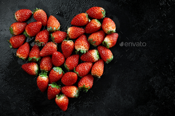 Fresh strawberries array heart shape on black background. Love concept ...