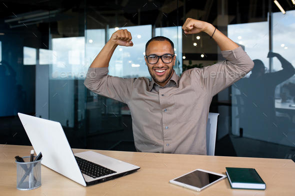 Happy man working in office showing muscles raising arms up, happy at ...