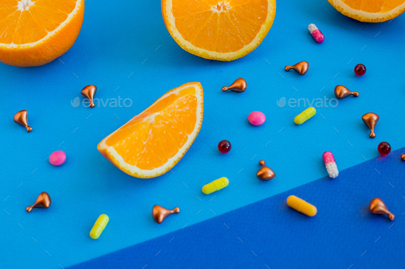 Multivitamins and supplements with fresh orange on blue background ...