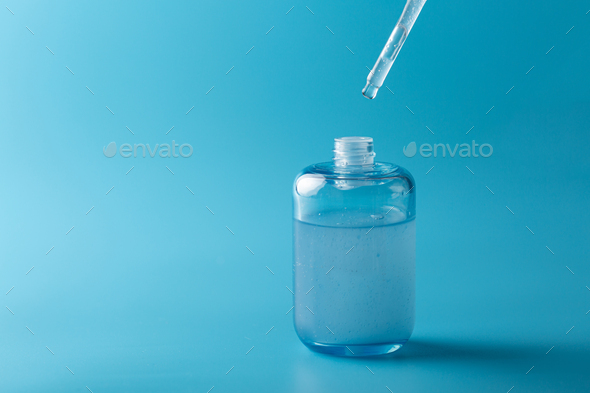 Serum pipette in close-up with a falling drop, cosmetic packaging with ...