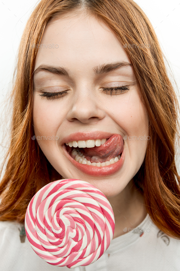 pretty red-haired woman eating lollipop enjoyment emotion close-up ...