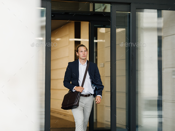 Male entrepreneur exiting from office building through automatic doors ...