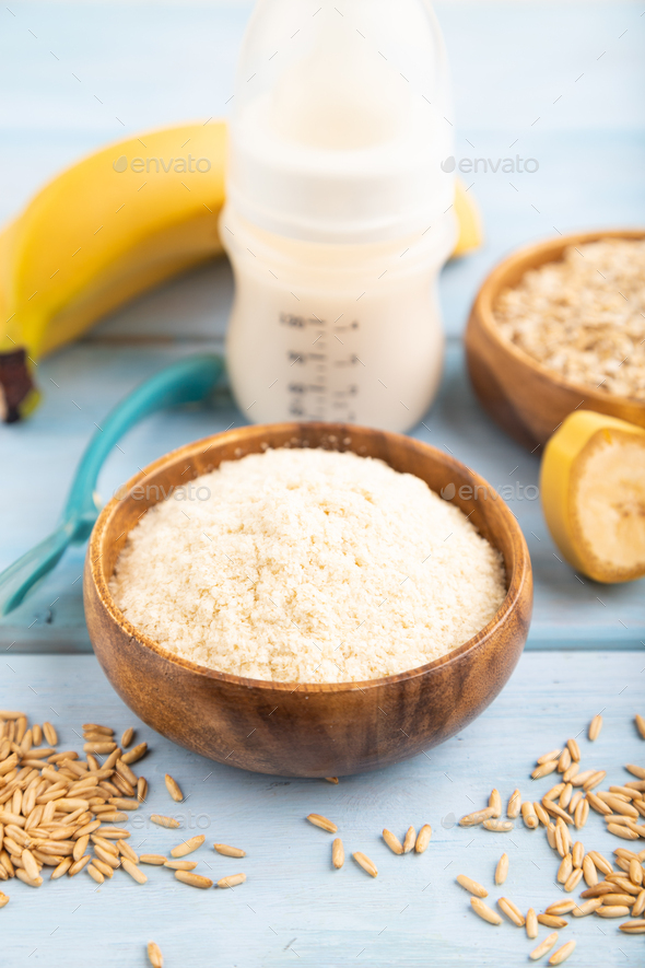 Powdered milk and oatmeal, banana baby food mix, on blue wooden, side ...