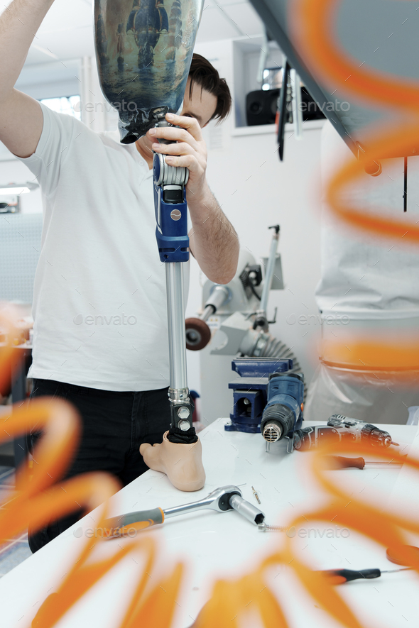 Crop unrecognizable craftsman adjusting and bending modern prosthetic ...