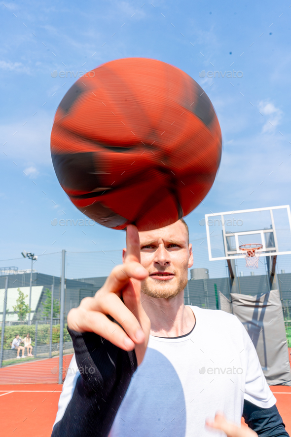 Close-up guy basketball player spinning a basketball on his finger ...