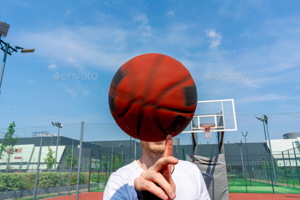 Close-up guy basketball player spinning a basketball on his finger ...