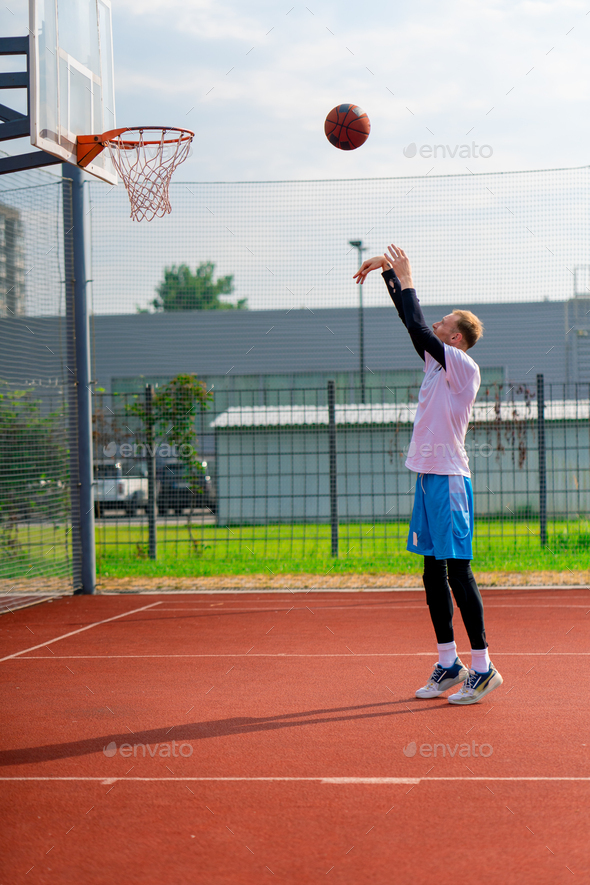 tall guy basketball player throws a ball into a basketball hoop at a ...