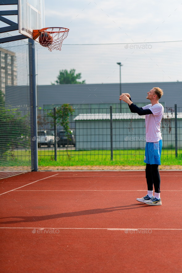 tall guy basketball player throws a ball into a basketball hoop at a ...