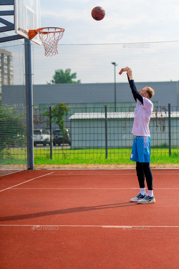 tall guy basketball player throws a ball into a basketball hoop at a ...
