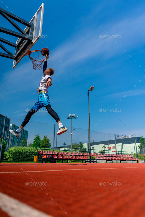 Tall guy basketball player jumps to the hoop with the ball in his hand ...