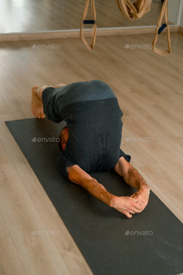 male yogi stretches his back lying on the floor to improve body ...