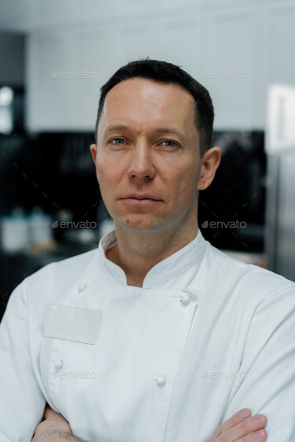 professional kitchen serious male chef in white coat standing at ...