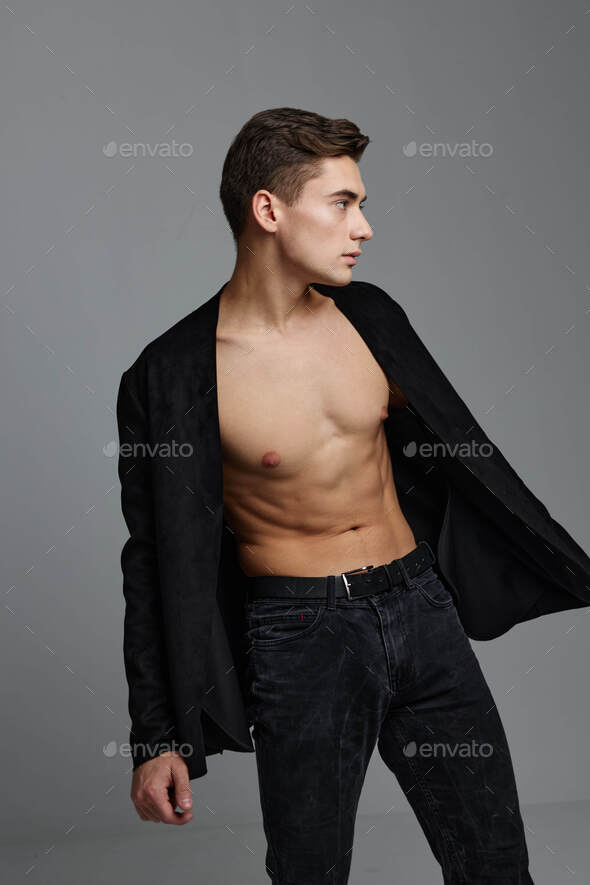 Handsome men in an unbuttoned shirt and trousers on a gray background ...