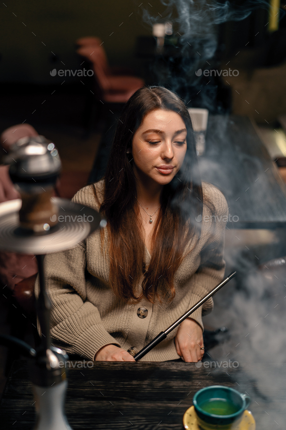 Beautiful young woman inhaling hookah girl smoking hookah sitting in lounge bar Stock Photo by ...