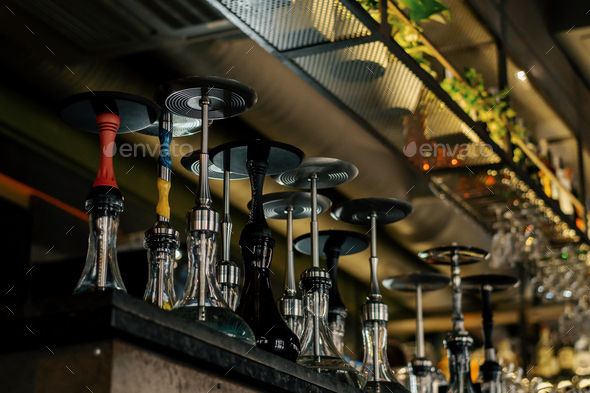 close-up of various hookahs with smoking equipment shelves in lounge ...