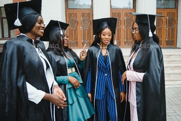 young graduates standing in front of university building on graduation ...