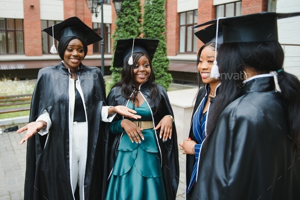 young graduates standing in front of university building on graduation ...