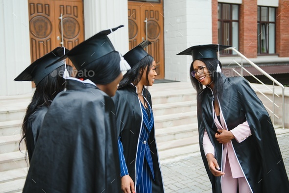 young graduates standing in front of university building on graduation ...