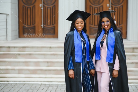 young graduates standing in front of university building on graduation ...