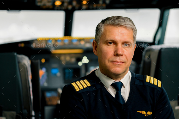 Portrait of serious airplane captain in uniform preparing for flight in ...