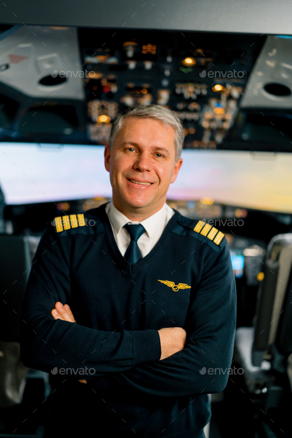 Portrait of smiling airplane captain in uniform preparing for flight in ...