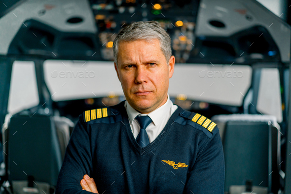 Portrait of serious airplane captain in uniform preparing for flight in ...
