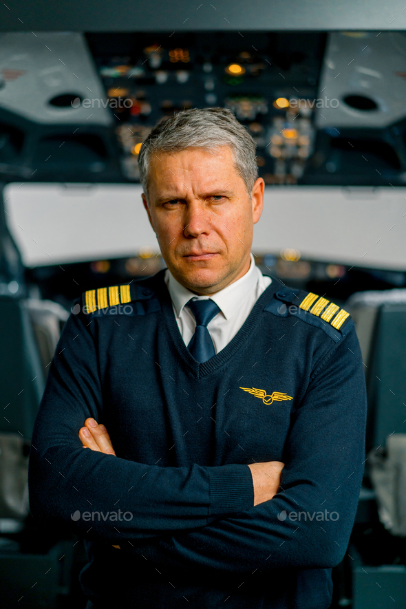 Portrait of serious airplane captain in uniform preparing for flight in ...