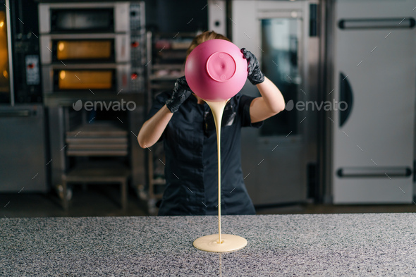 Pastry chef pours melted chocolate on stone table for tempering ...