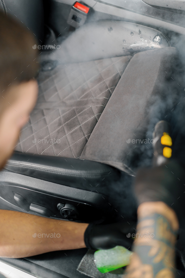 The detailing master cleans the car interior with a hot steam cleaner ...