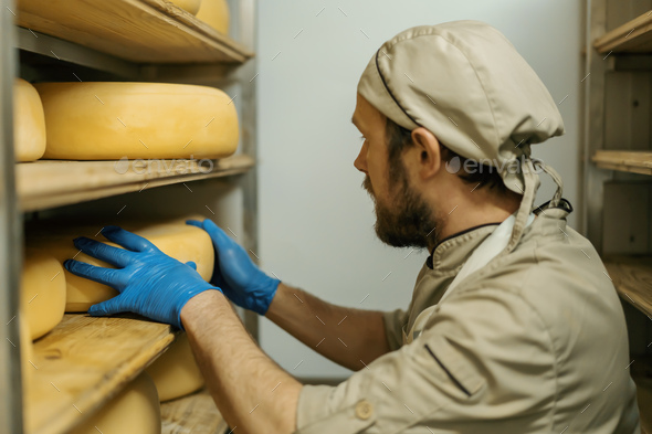 cheese maker in uniform at cheese production man in warehouse with ...
