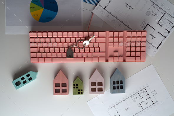 Colorful model houses on blueprints with a key to the new home close-up ...