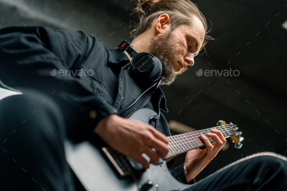 rock performer with electric guitar in recording studio creating song ...