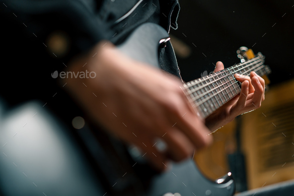 rock performer with electric guitar in recording studio creating song ...