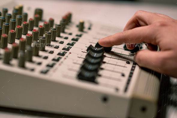 professional recording studio sound engineer with finger adjusts volume ...