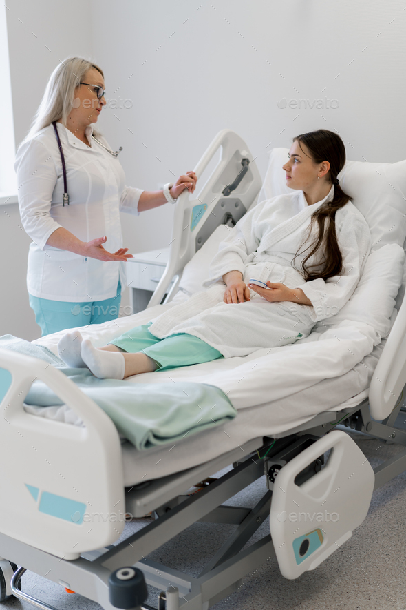 doctor standing by the bed in a hospital room and discussing a ...