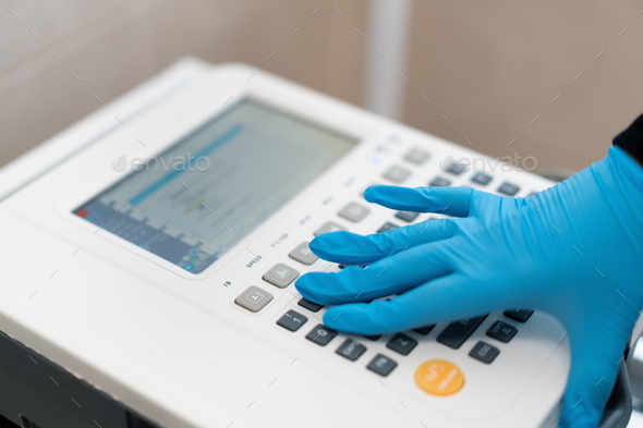 a cardiologist enters data on the display of an ECG machine to perform ...