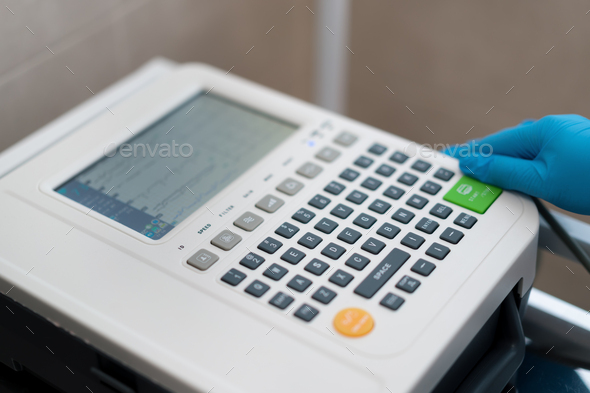 a cardiologist enters data on the display of an ECG machine to perform ...