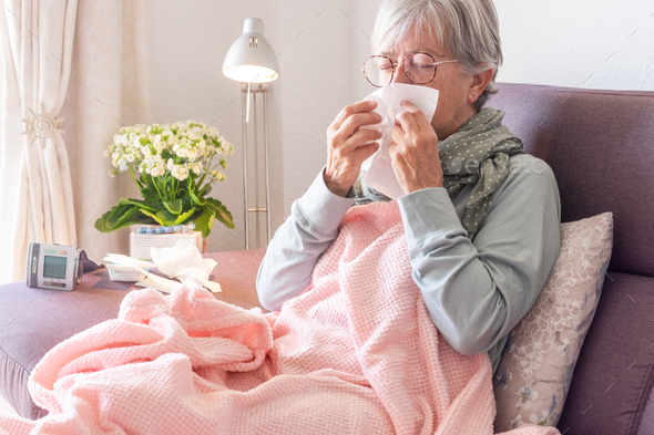Older adult caucasian woman with severe cold and fever symptoms such as ...