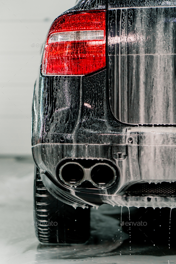 Close-up of car foam application on the trunk, rear bumper and exhaust ...