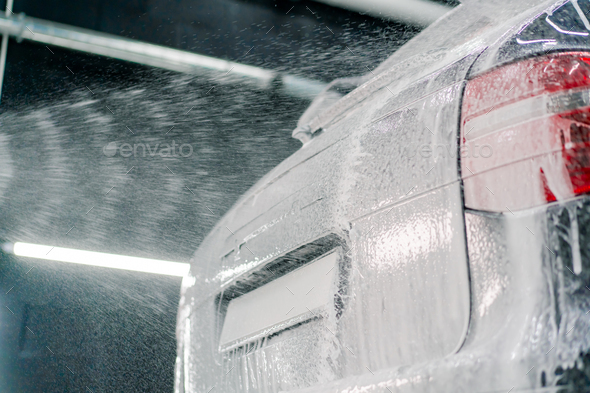 Close-up of car foam application on the trunk rear bumper and exhaust ...