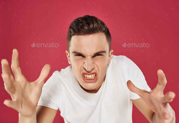 disgruntled man with an angry expression in a white t-shirt gesturing ...
