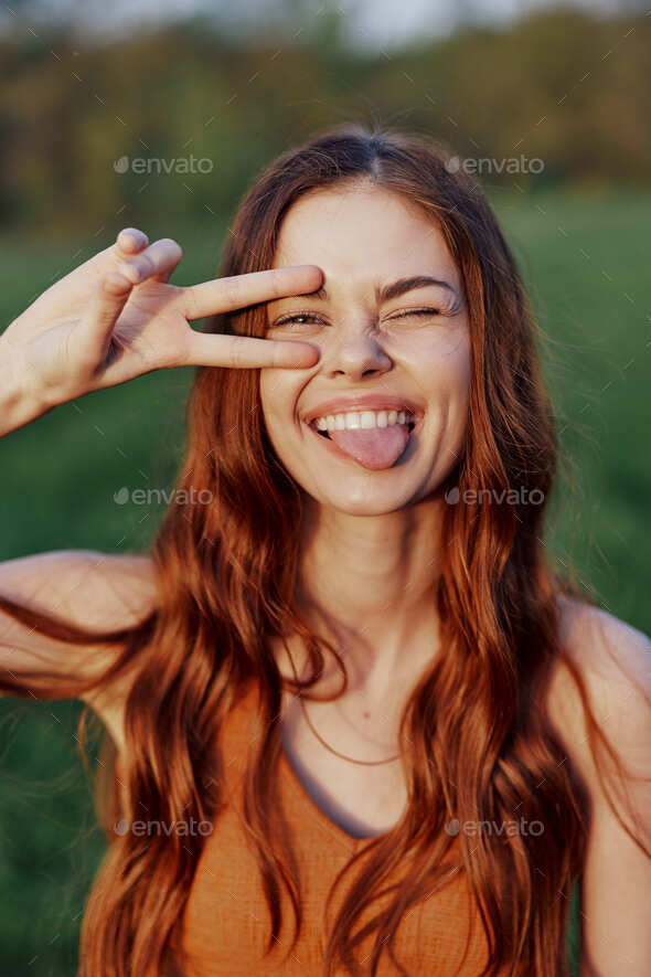 A beautiful smile of a woman with red hair shows her tongue. Cute girl ...