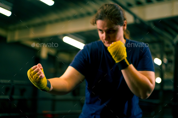 portrait focused Boxer girl in yellow boxing bandages standing in a ...