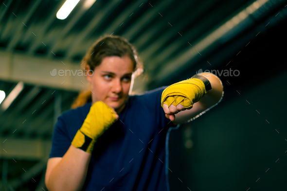 portrait focused Boxer girl yellow boxing bandages standing in a boxing ...